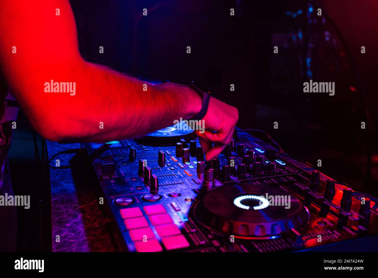 hands of a DJ mixing music on a professional controller in a booth at a ...
