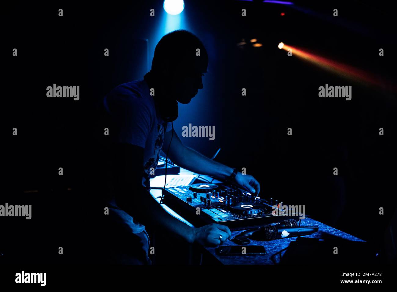 DJ plays electronic music on the mixer at a concert in a nightclub ...
