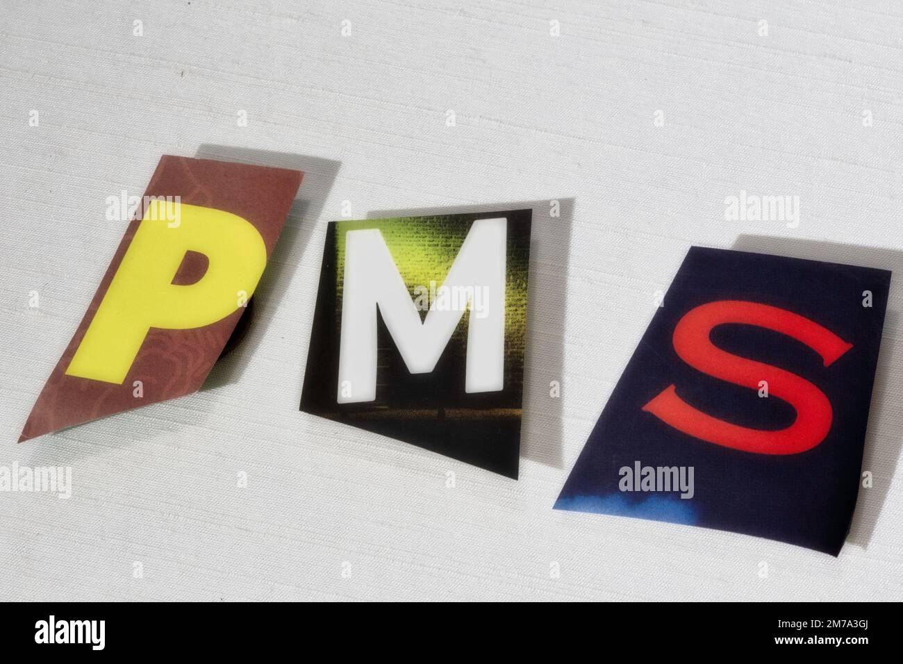 The acronym "PMS" (Premenstrual Syndrome) using cut-out paper letters ...