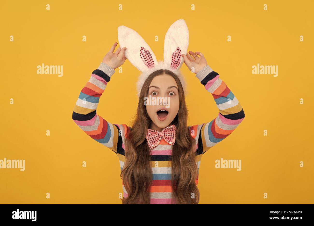 amazed easter child in bunny ears and bow tie on yellow background ...