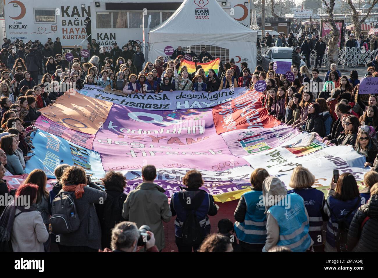 Demonstrators hold a large piece of joined banners as they chant ...