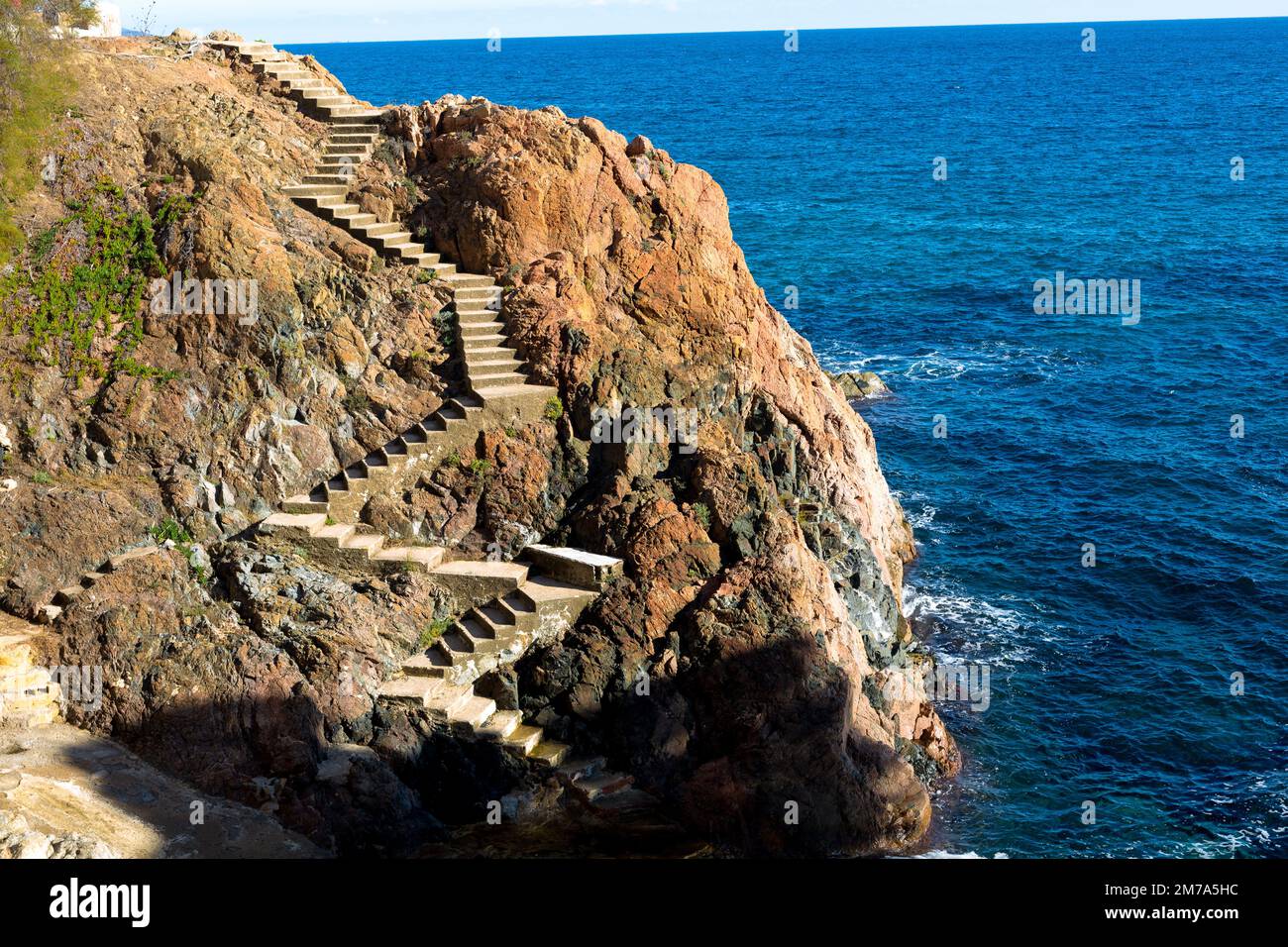 stairs leading down to a small beach by the rock cliff on the Costa ...