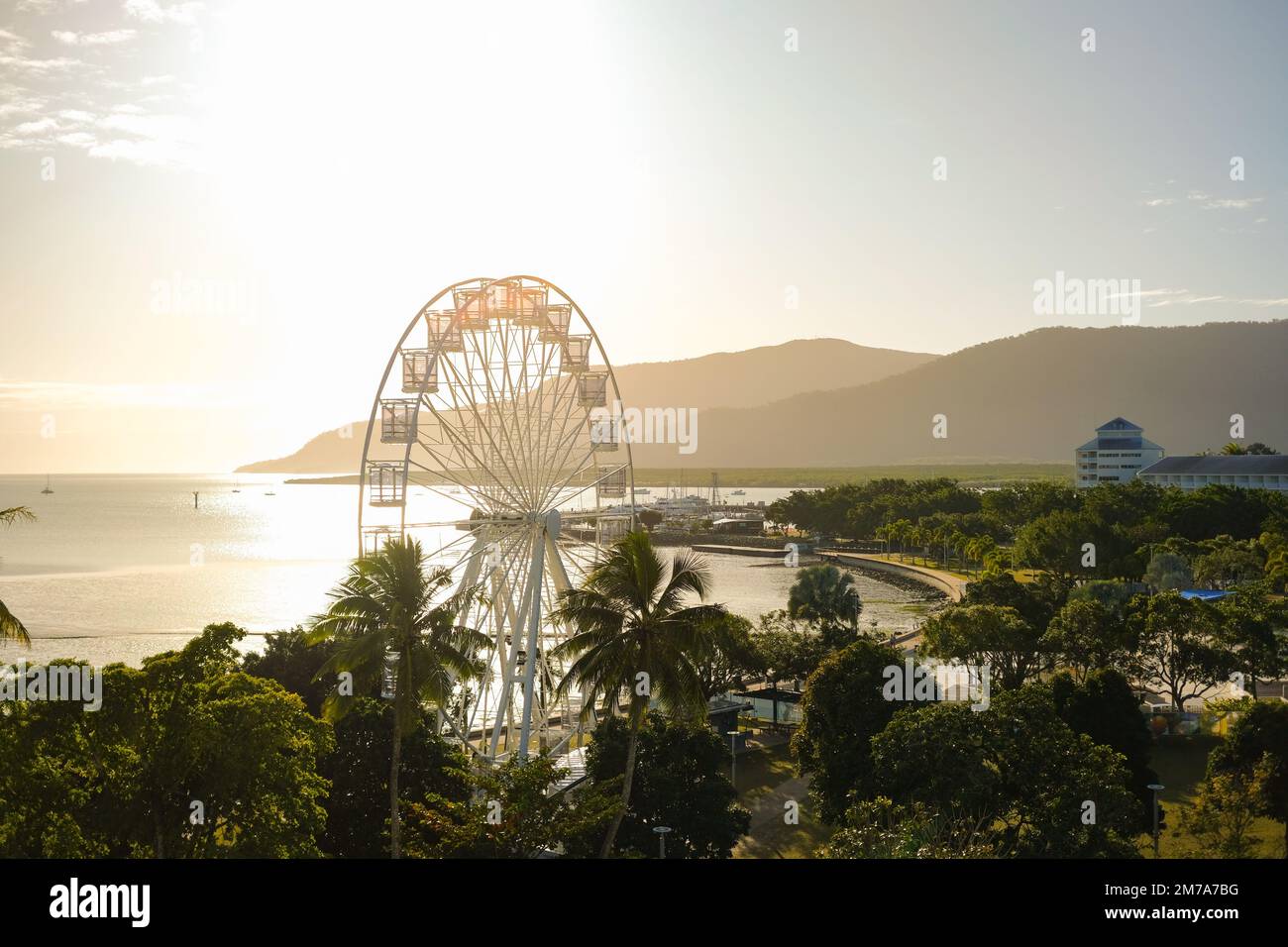 Golden hour over the ferris wheel, treetops, lagoon and hilly backdrop ...