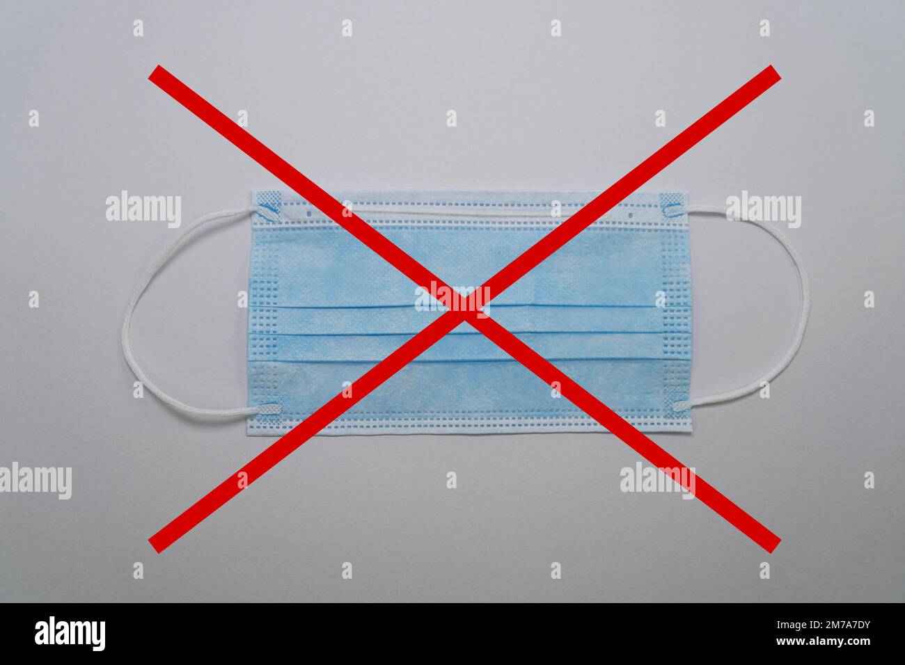 Blue medical mask on a gray background crossed out with red lines ...