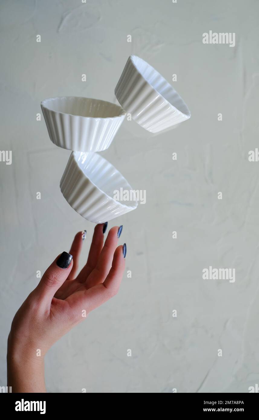 Woman hand and flying white bowls in levitation Stock Photo - Alamy