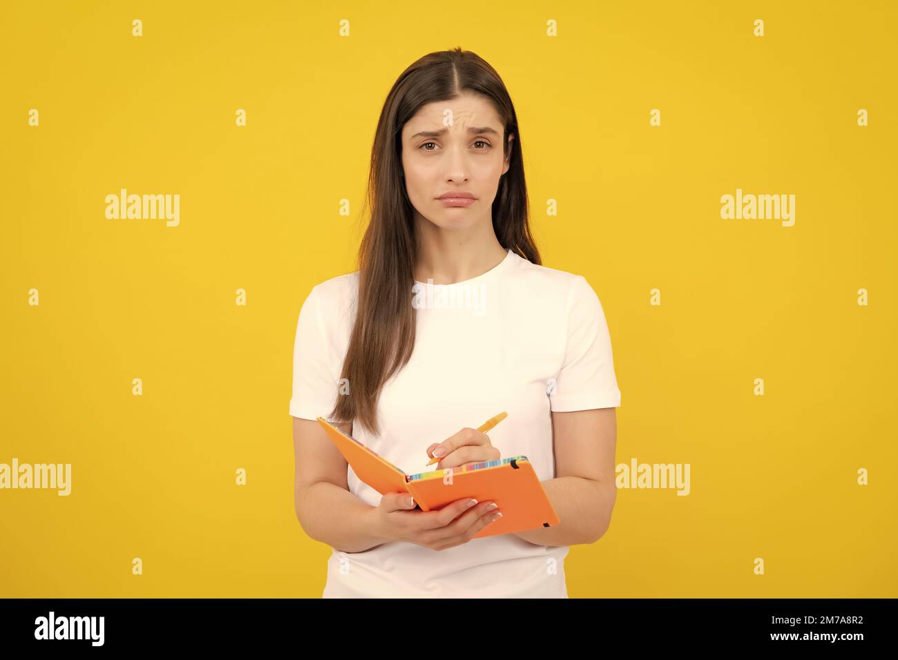 Sad tired woman isolated over yellow background writing notes in ...