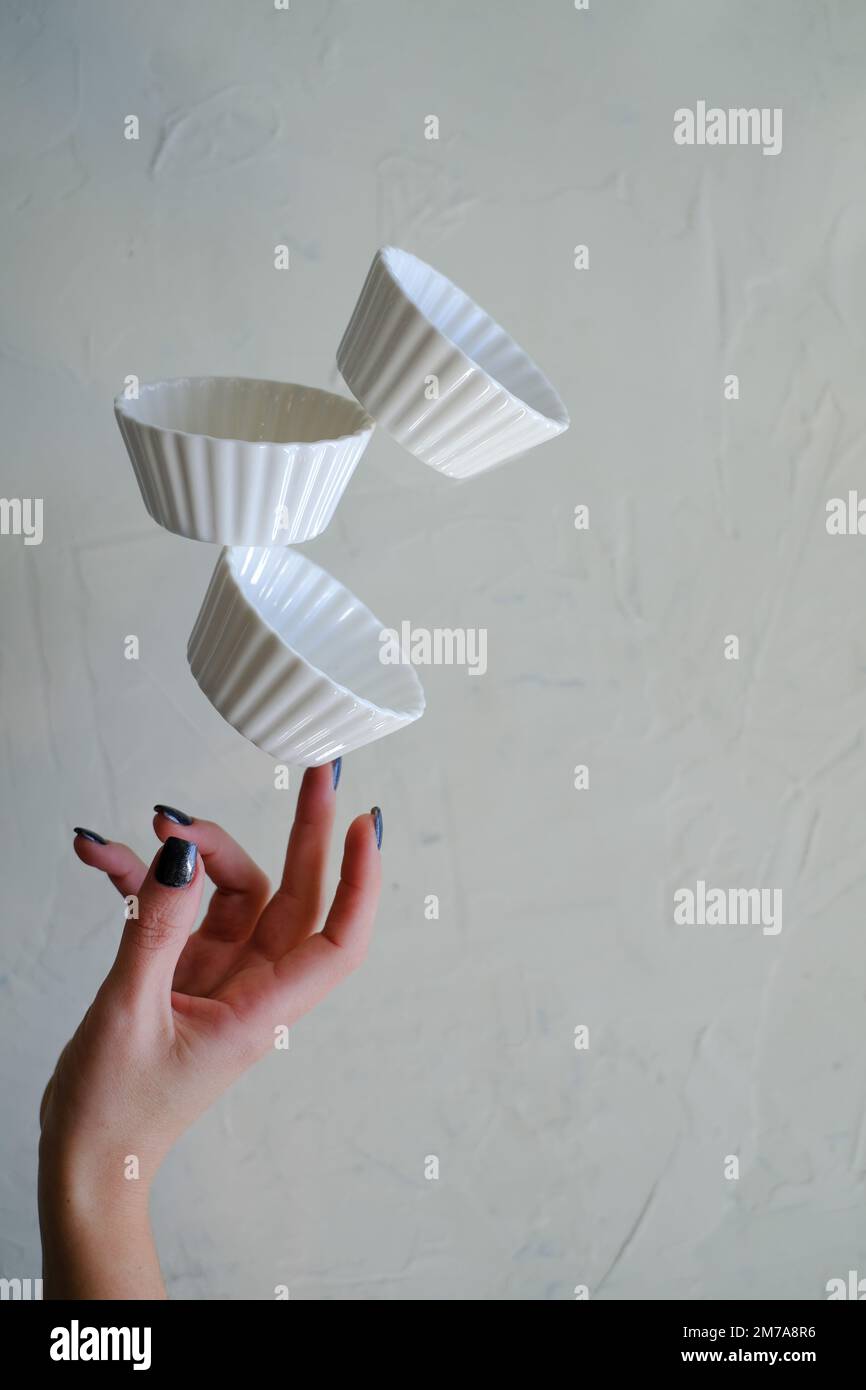 Woman hand and flying white bowls in levitation Stock Photo - Alamy