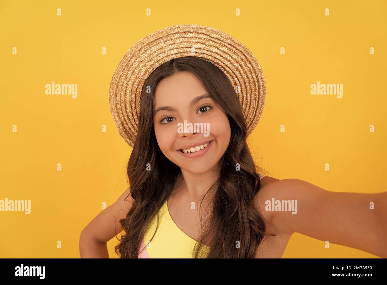 happy kid in summer straw hat making selfie on yellow background ...