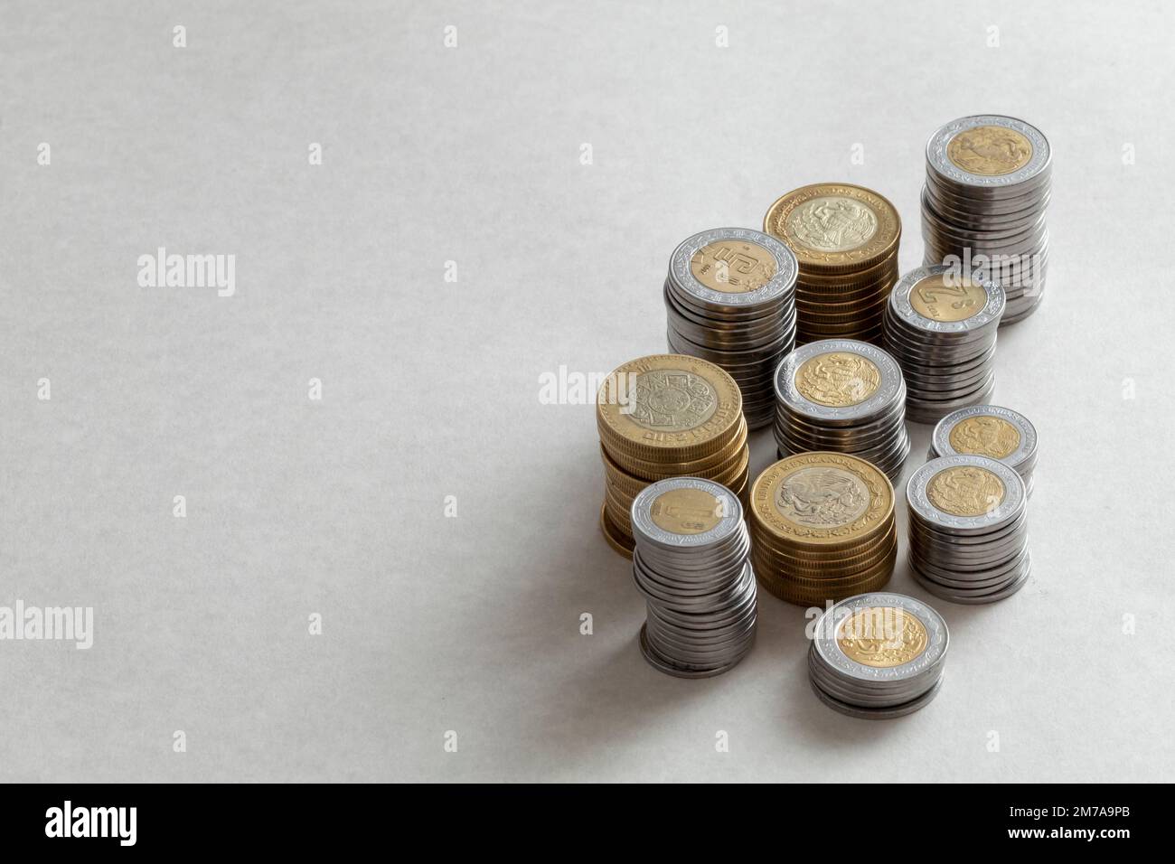 Mexican peso coins of different denominations stacked on a table with ...