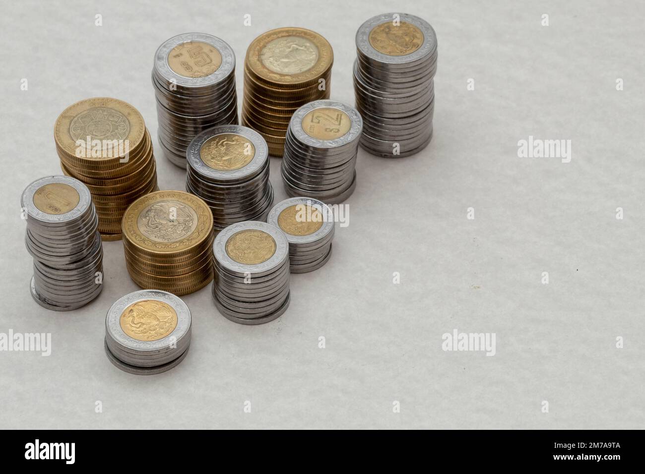 Mexican peso coins of different denominations stacked on a table with ...