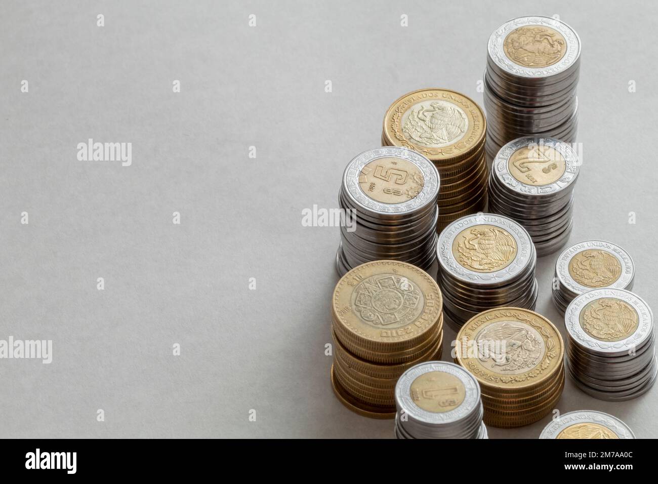 Mexican peso coins of different denominations stacked on a table with ...