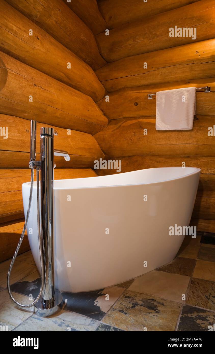 White freestanding oval bathtub in bathroom with ceramic tile floor ...