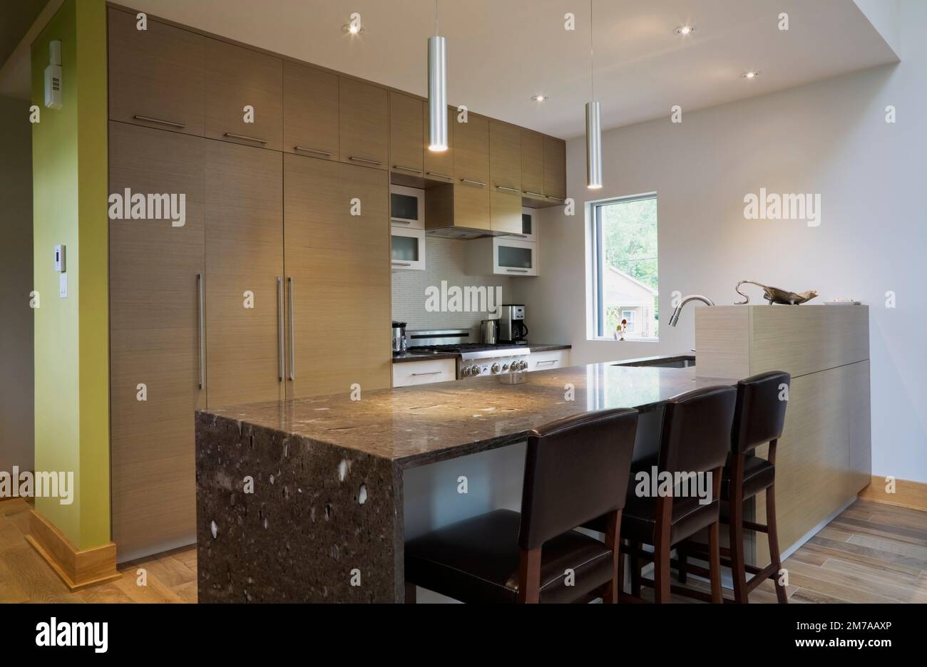 Island with dark grey granite countertop and high back leather and wood ...