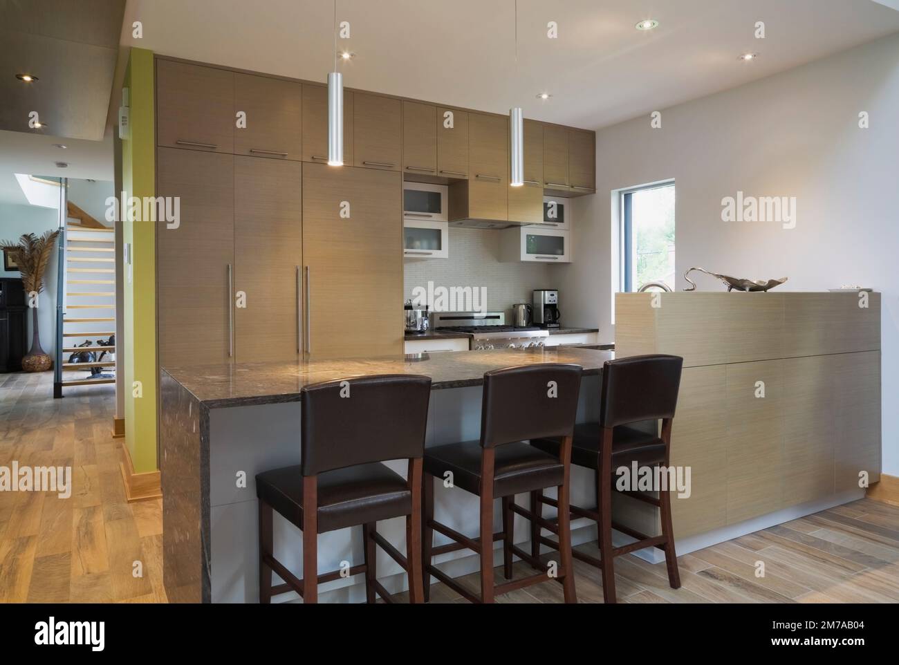 Island with dark grey granite countertop and high back leather and wood ...