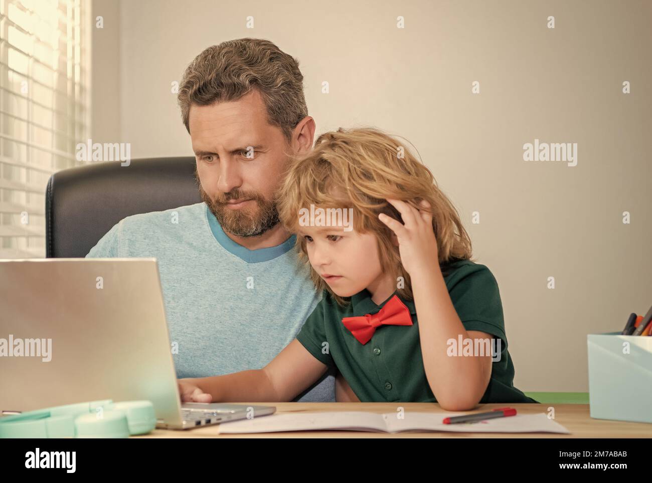 bearded dad or school private tutor teaching boy son with modern laptop ...