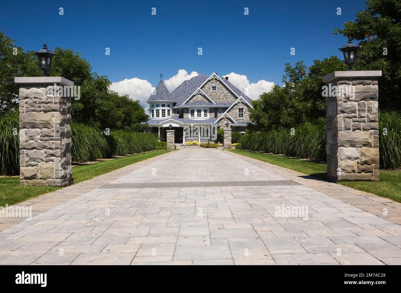 Paving stone alley with stone columns bordered by Miscanthus ...