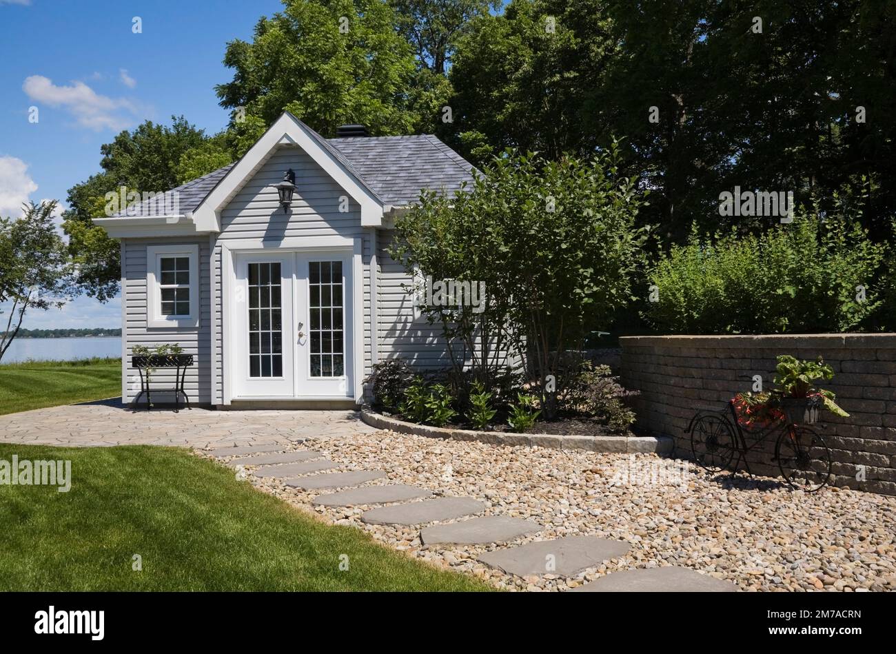 Rock bed with path stones leading to grey with white trim storage shed ...