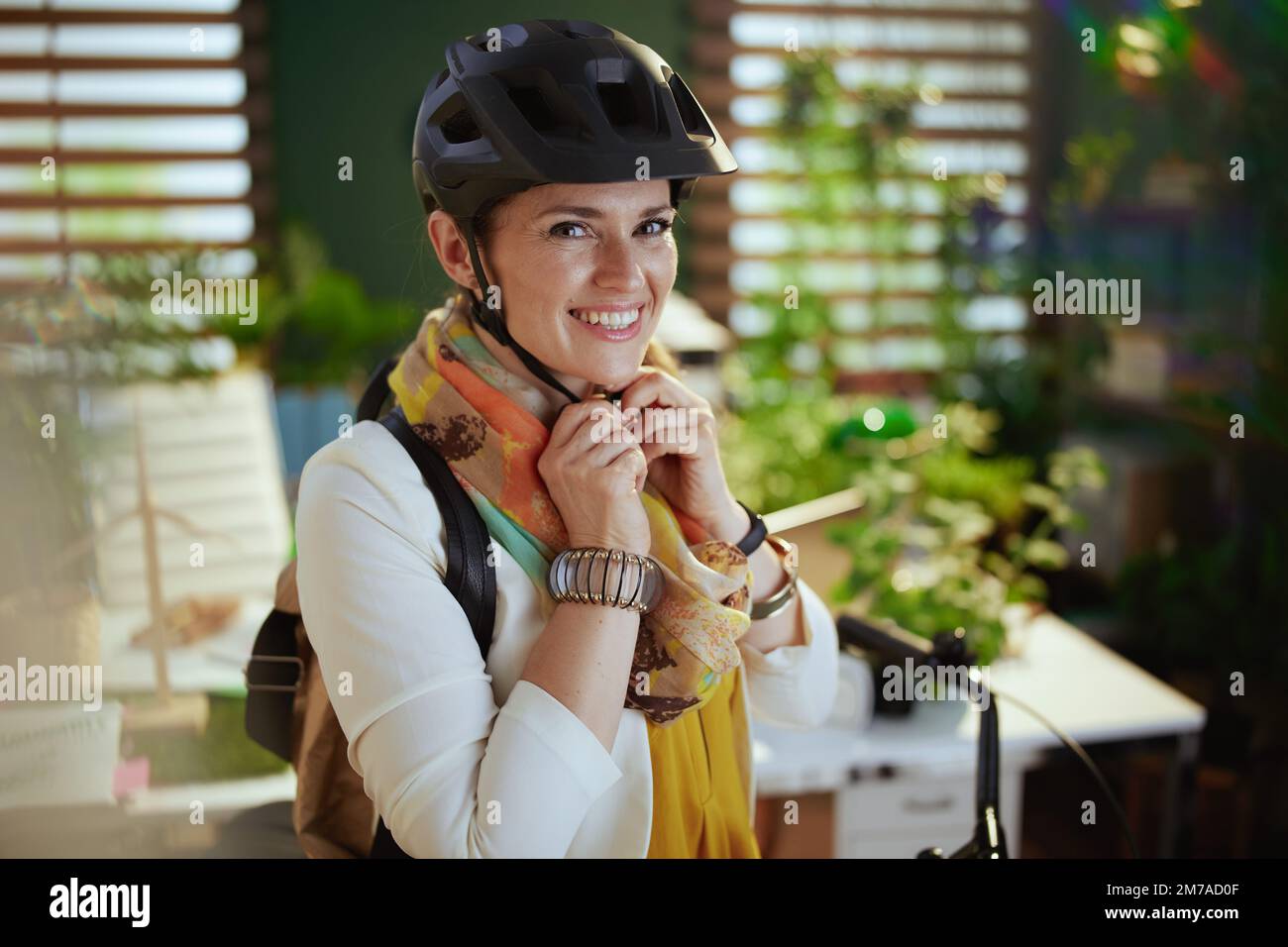 Portrait of smiling modern business woman in bike helmet in modern eco ...