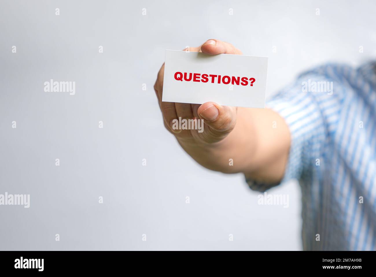 Man holding a white business card with text, Questions Stock Photo - Alamy