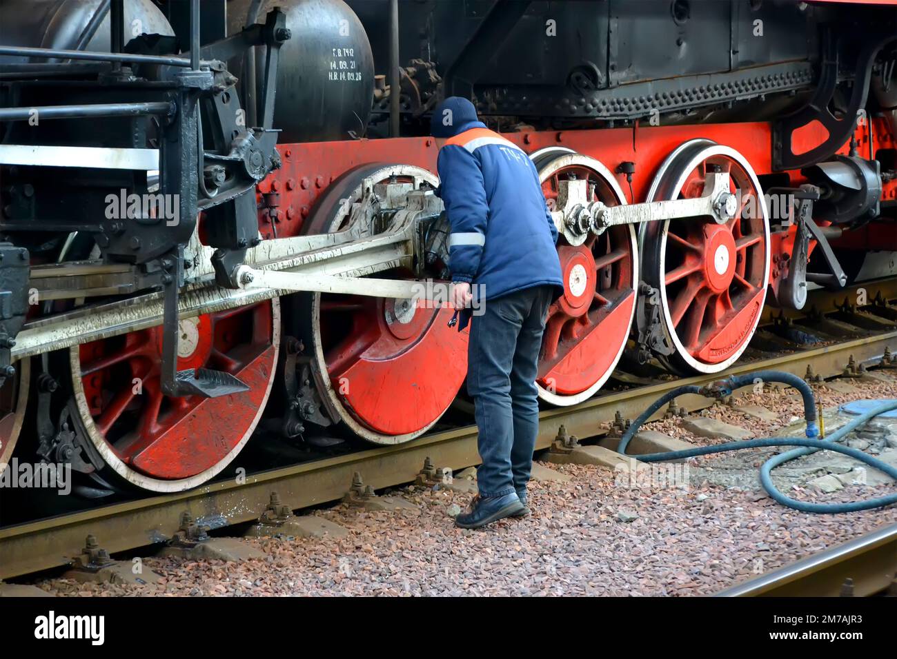 worker checks the mechanical parts of a retro steam locomotive wheelset ...