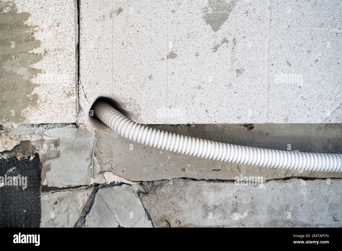 The wire in a protective plastic corrugated pipe is laid through the ...