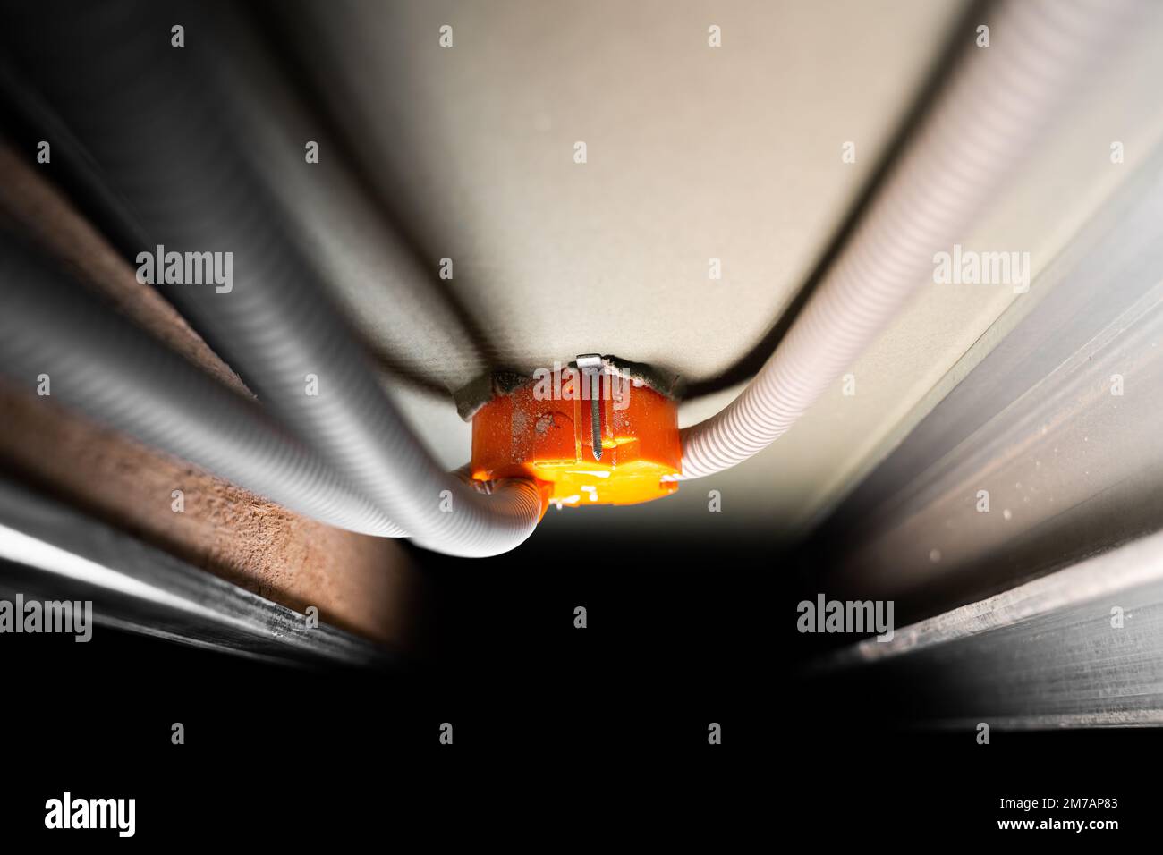 Orange socket box in drywall with wires in a protective corrugated pipe ...