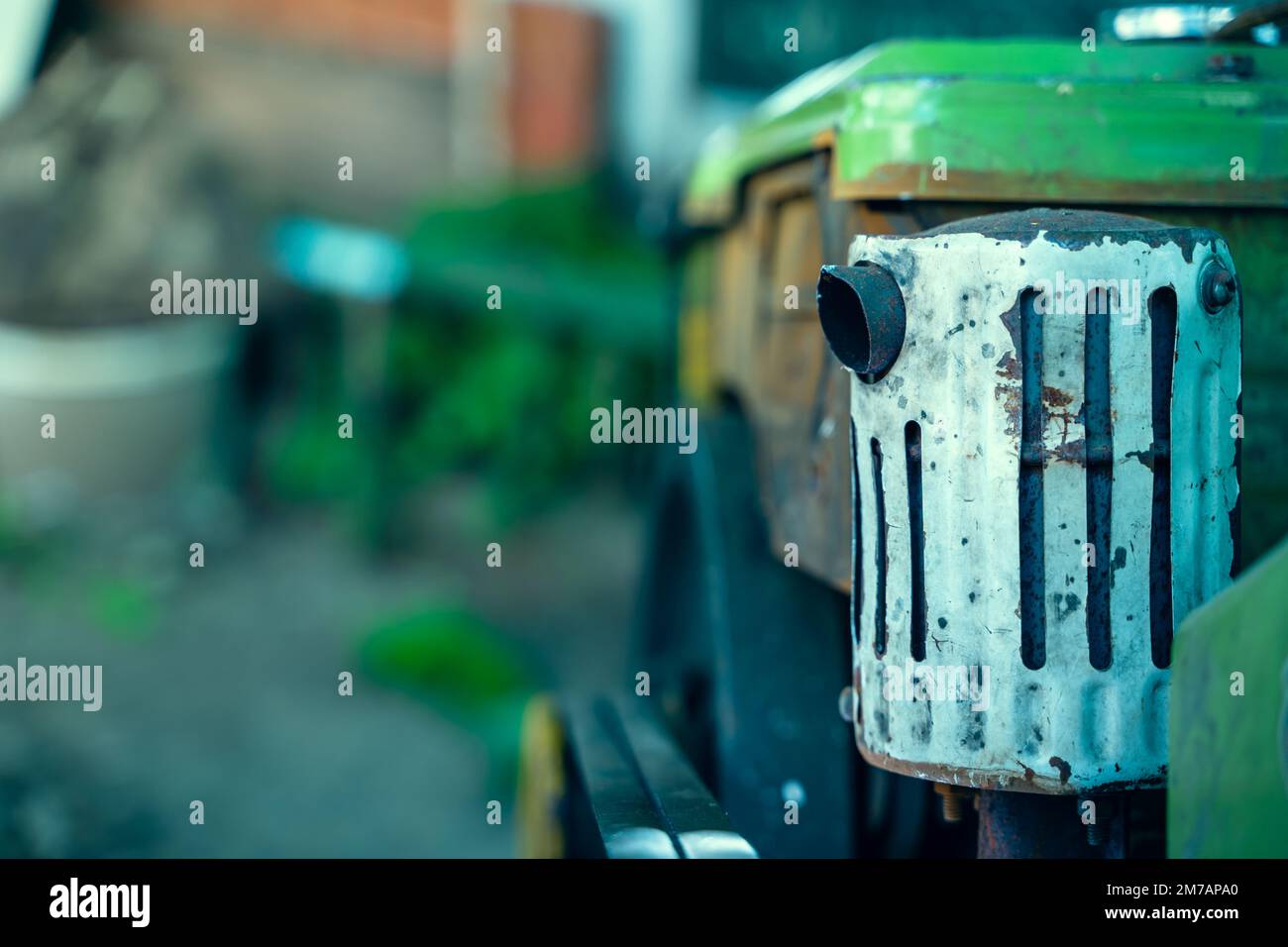 The muffler of the exhaust pipe of a walk-behind tractor against the ...