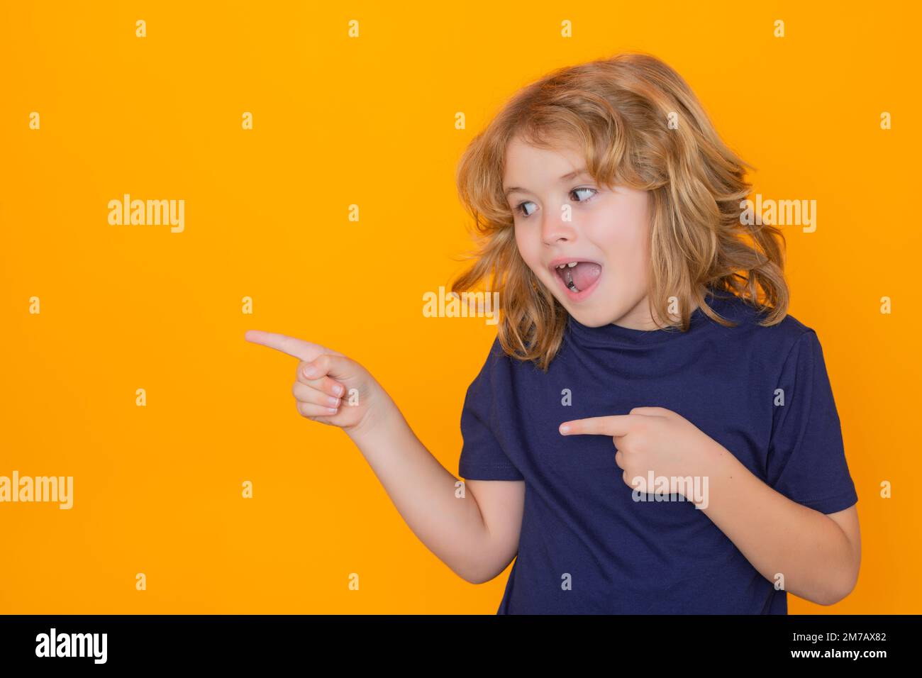 Excited kid boy on studio isolated background. Kid pointing finger away ...