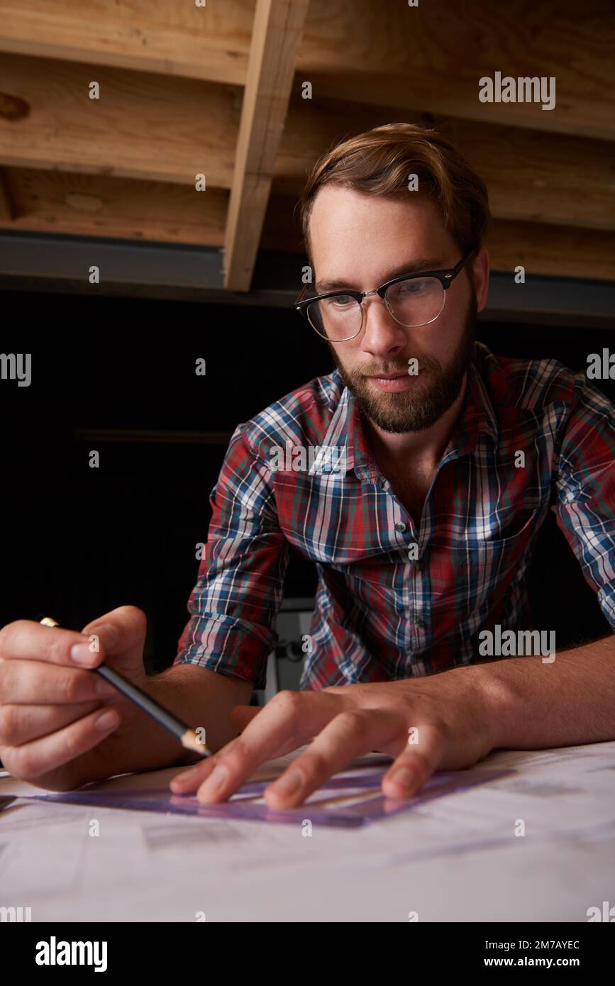 Perfecting the plans before construction starts. a young male architect ...