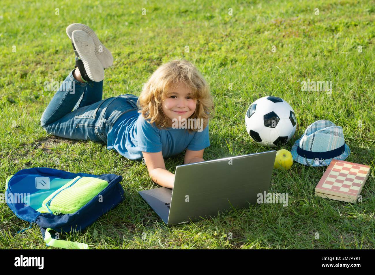 Summer vacation homework. Cute smiling child use computer on green ...