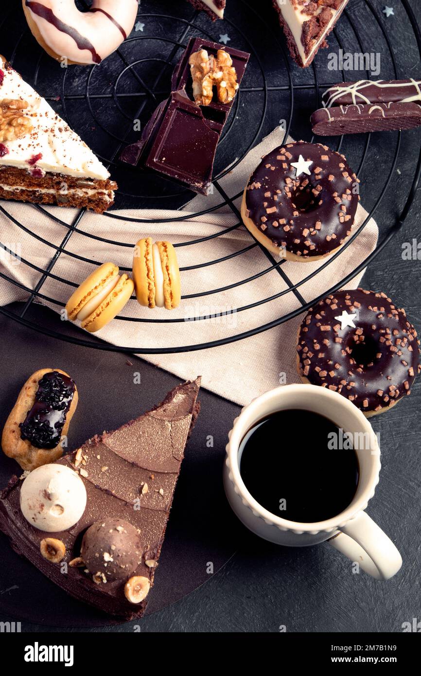 Table with various cookies, donuts, cakes, cheesecakes on dark ...