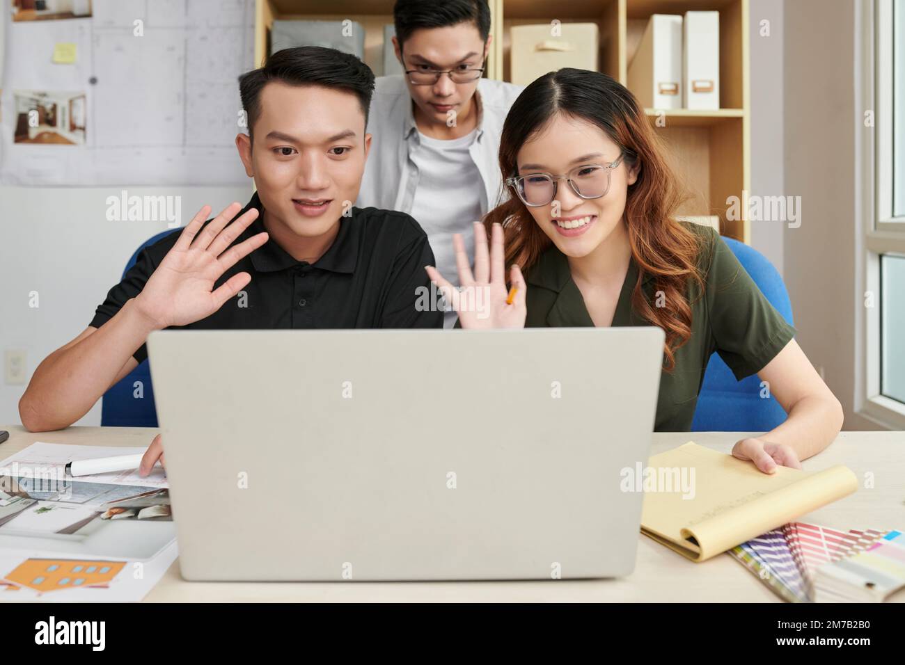 Team of young architects and interior designers video calling client ...