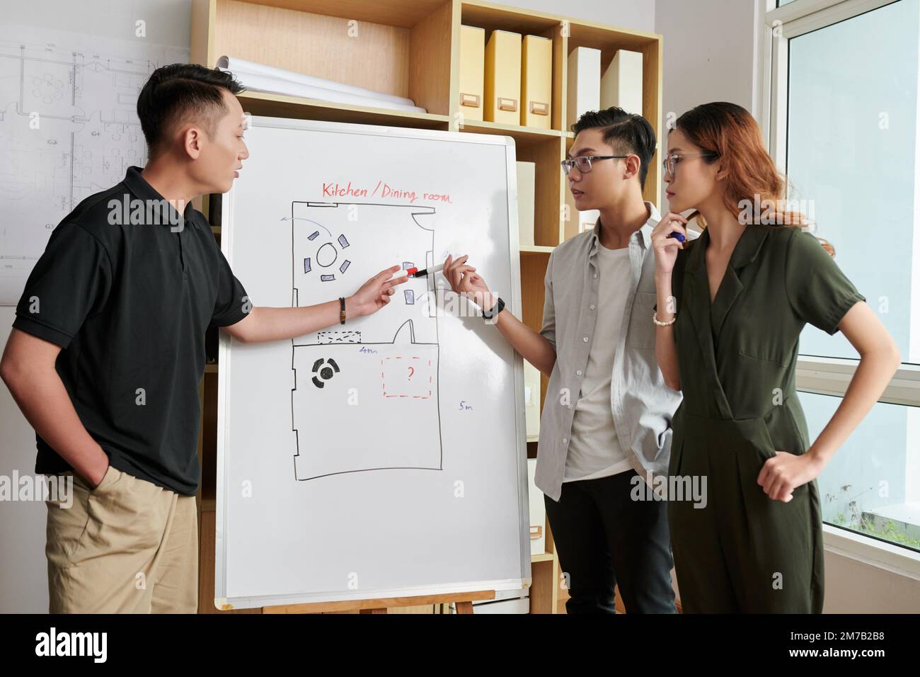 Group of architects and interior designers drawing plan on whiteboard ...