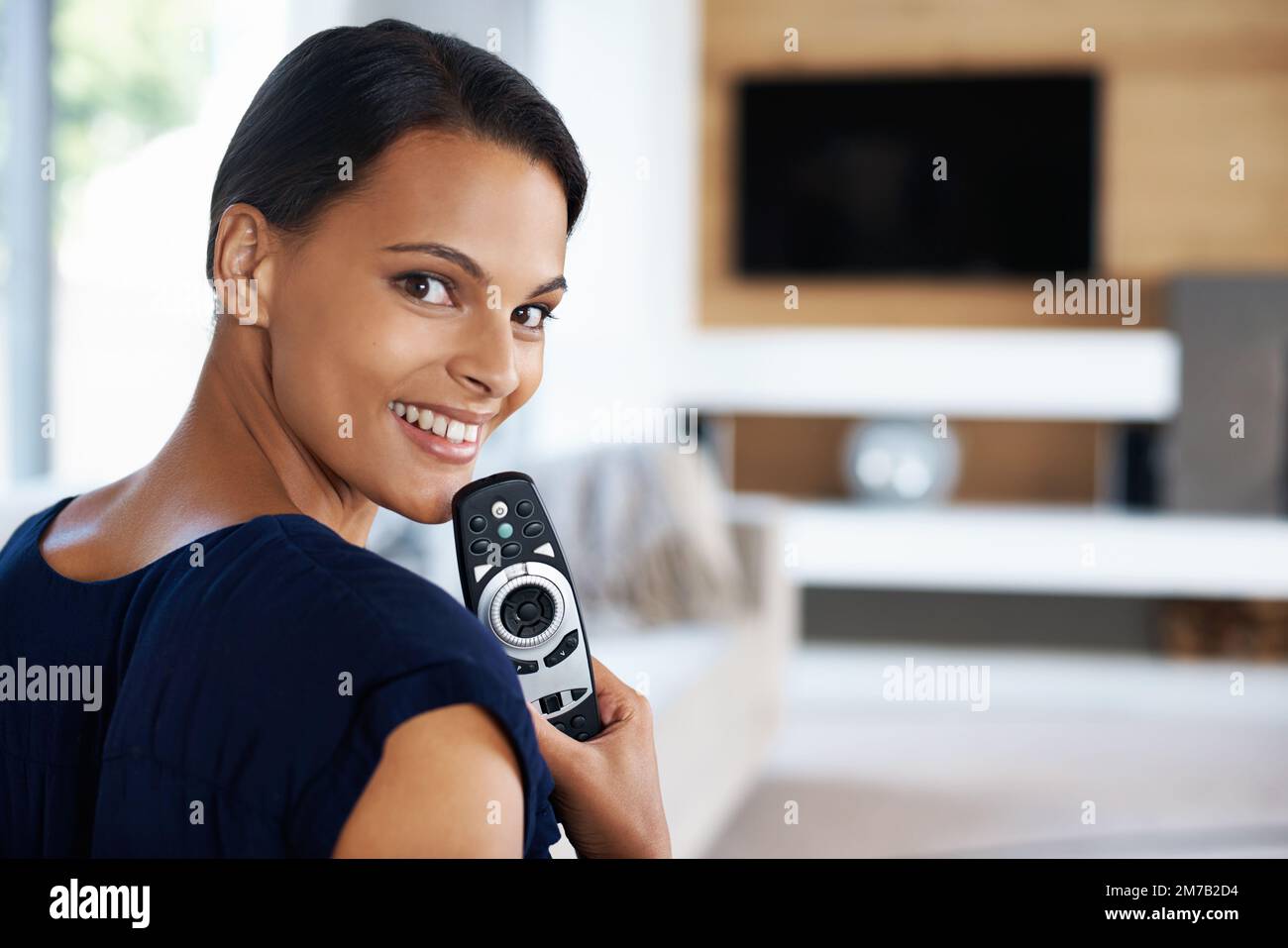 Totally in control. a happy young woman with a remote control looking ...