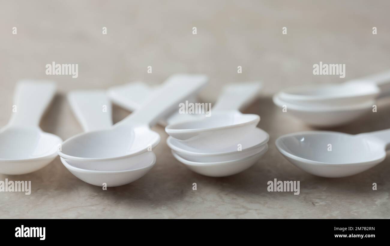 Disposable plastic spoons on marble background Stock Photo - Alamy