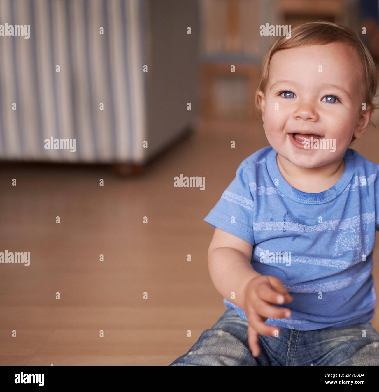 The cutest smile. an adorable little infant sitting on the floor Stock ...