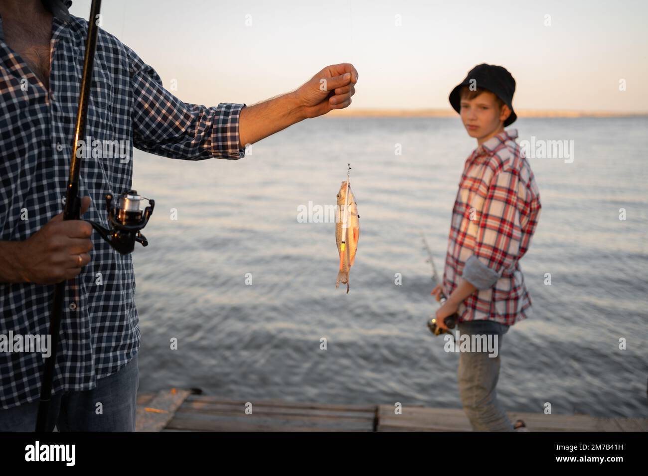 Man caught a fish boy son in the background Stock Photo - Alamy
