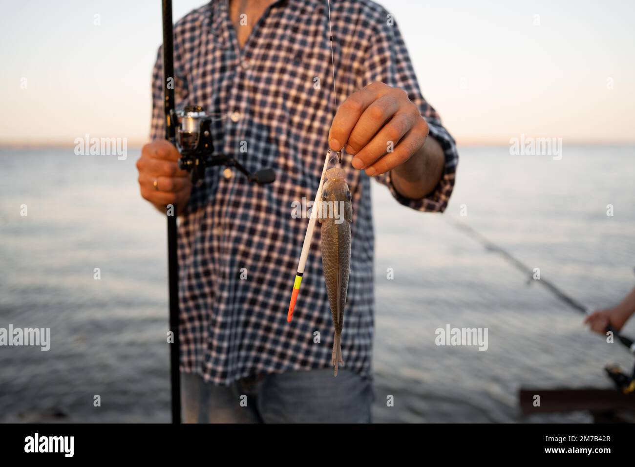 Success fishing. fisherman with fishing rod and small fish trophy at ...
