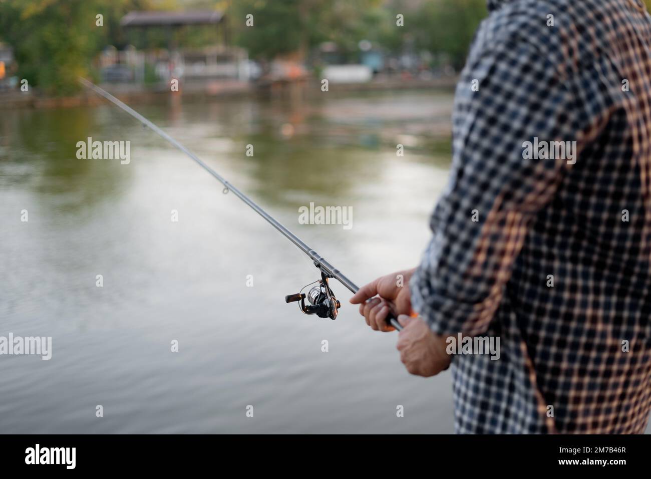Fisherman with rod, spinning reel on the river bank. Sunrise. Summer ...