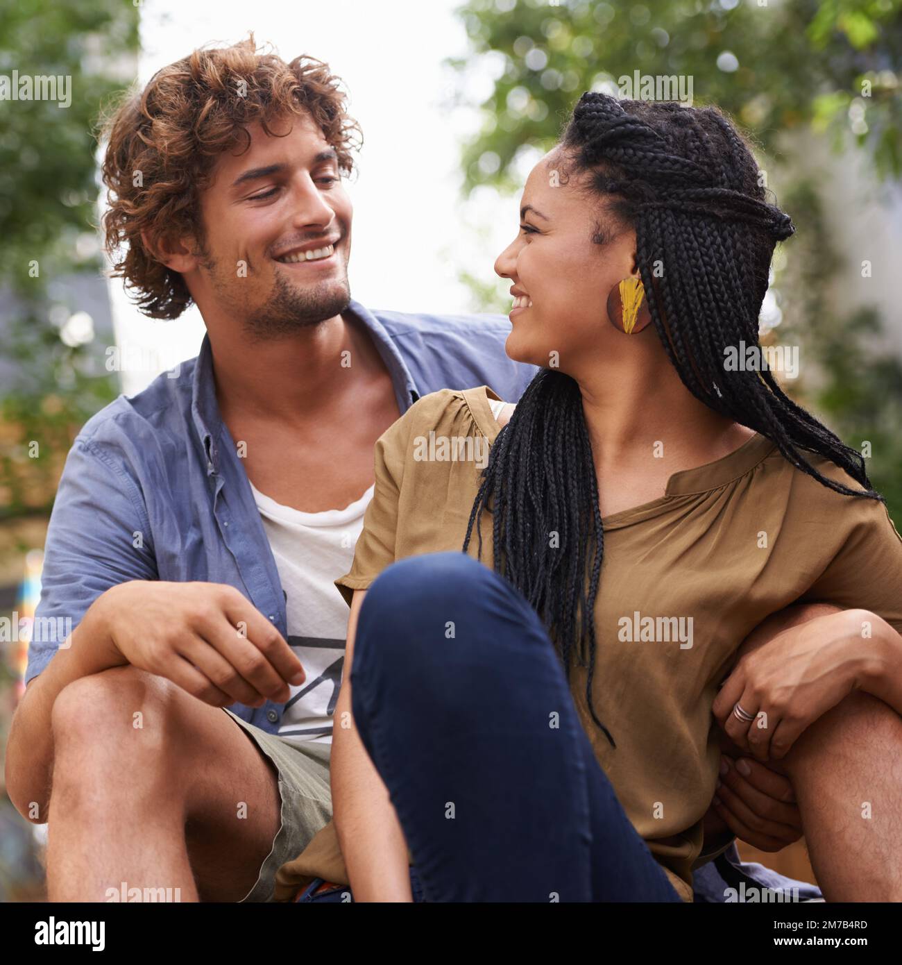Lost in each others eyes. an affectionate young couple sitting outdoors ...