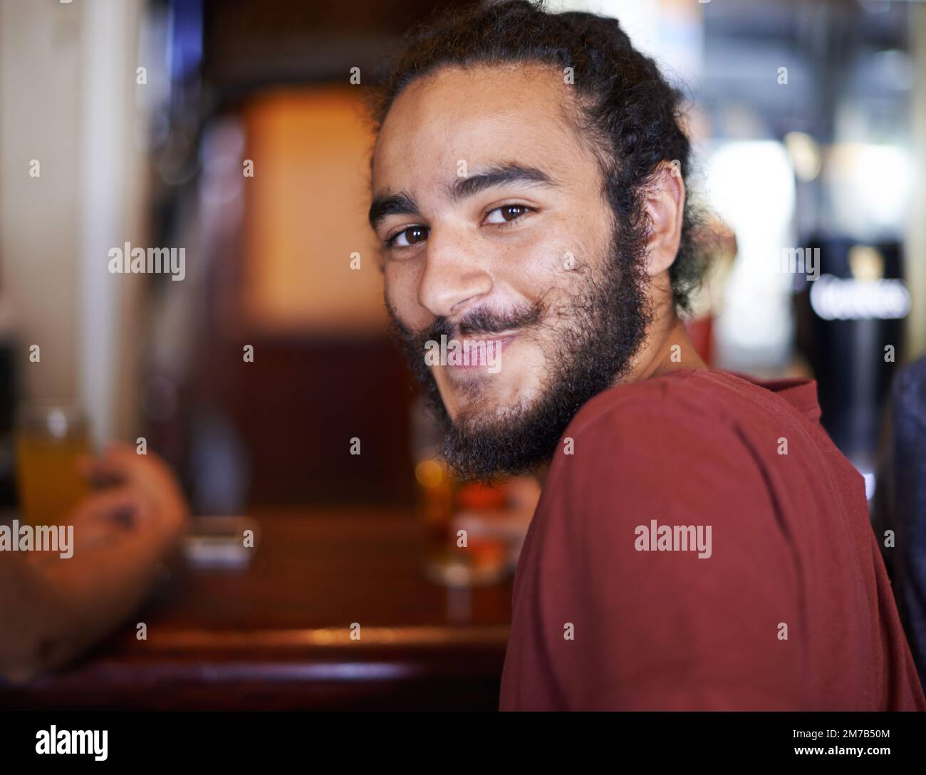 Never too early for a cold one. A happy young man sitting at a bar ...
