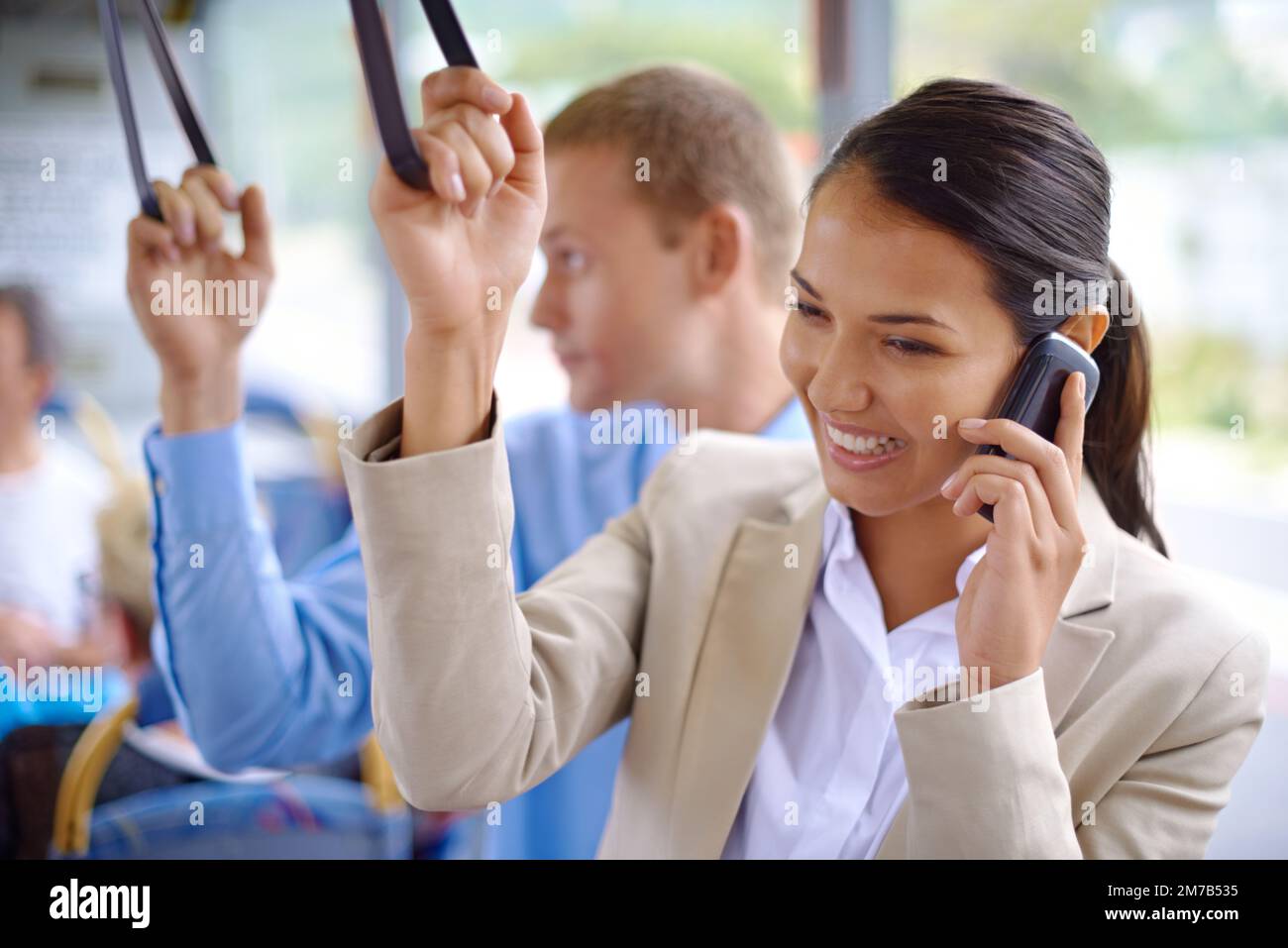 Staying connected in commute. Two young colleagues traveling on the bus ...