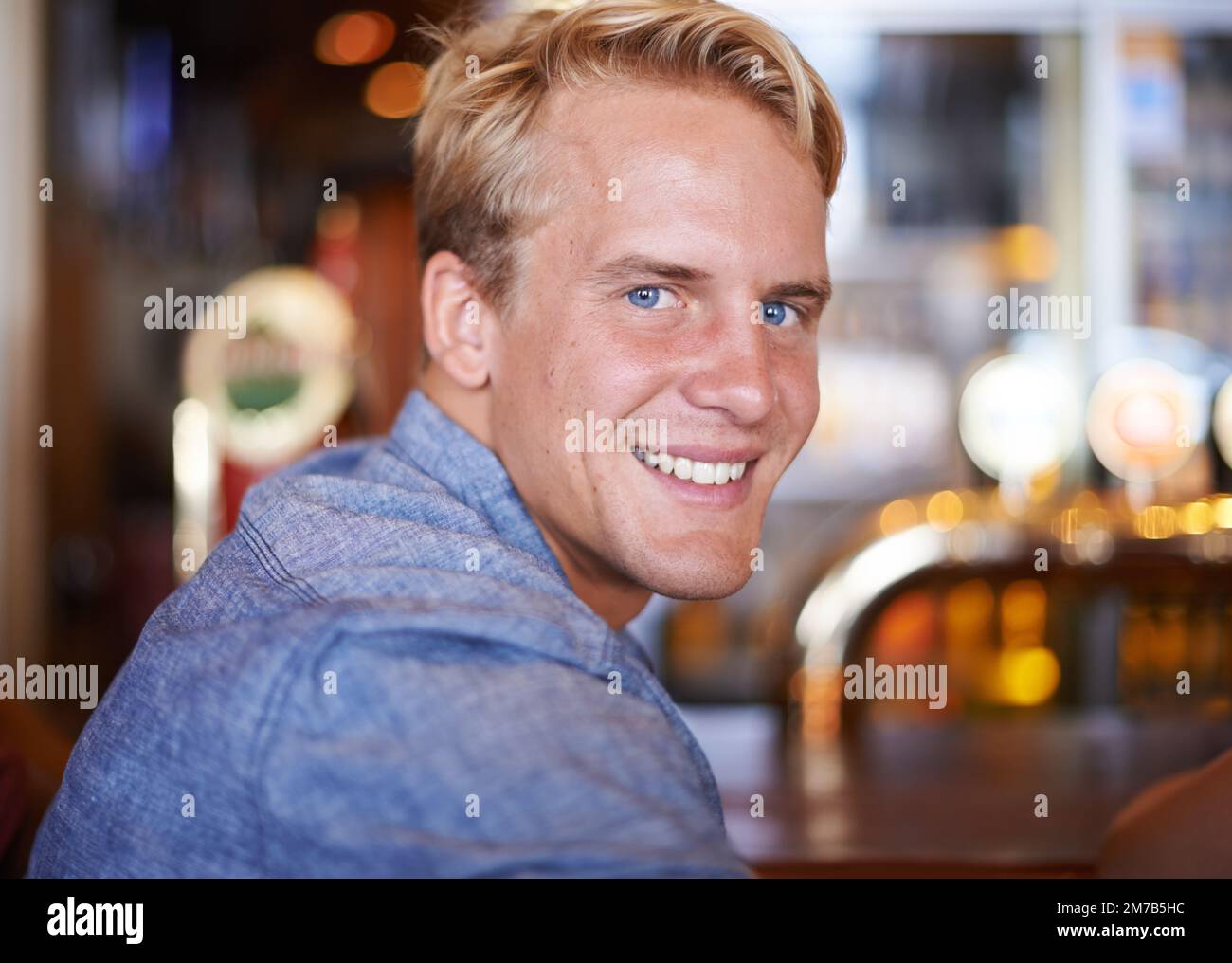 Keen for a pint. A portrait of a happy young man sitting in a pub Stock ...