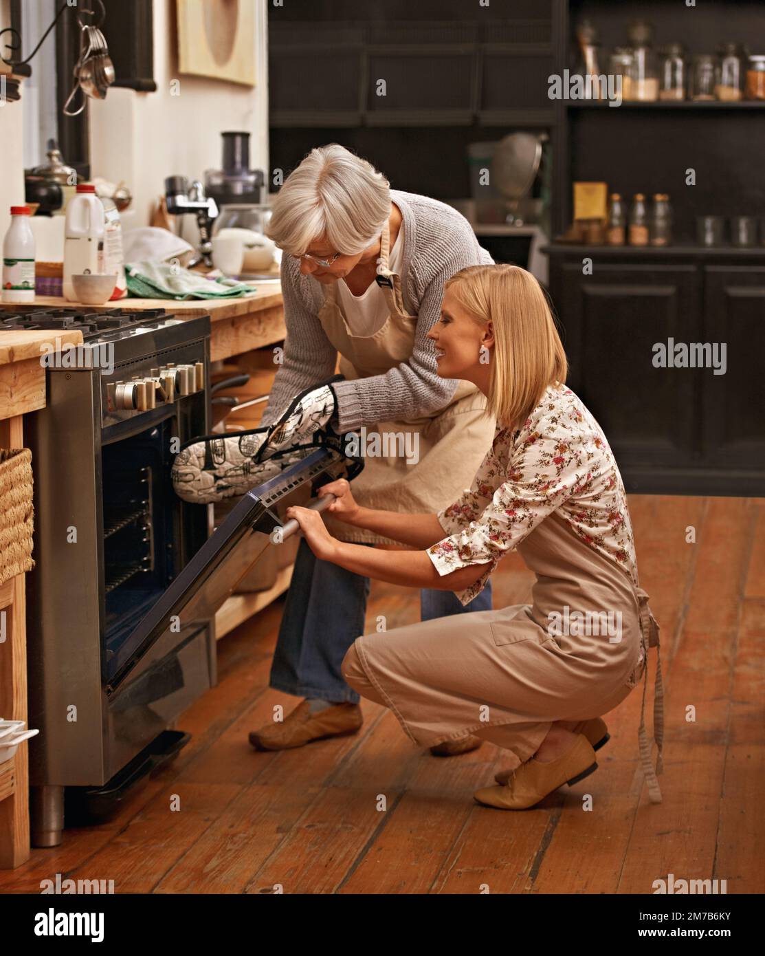 Checking to see if its done. young woman learning baking tips from her ...