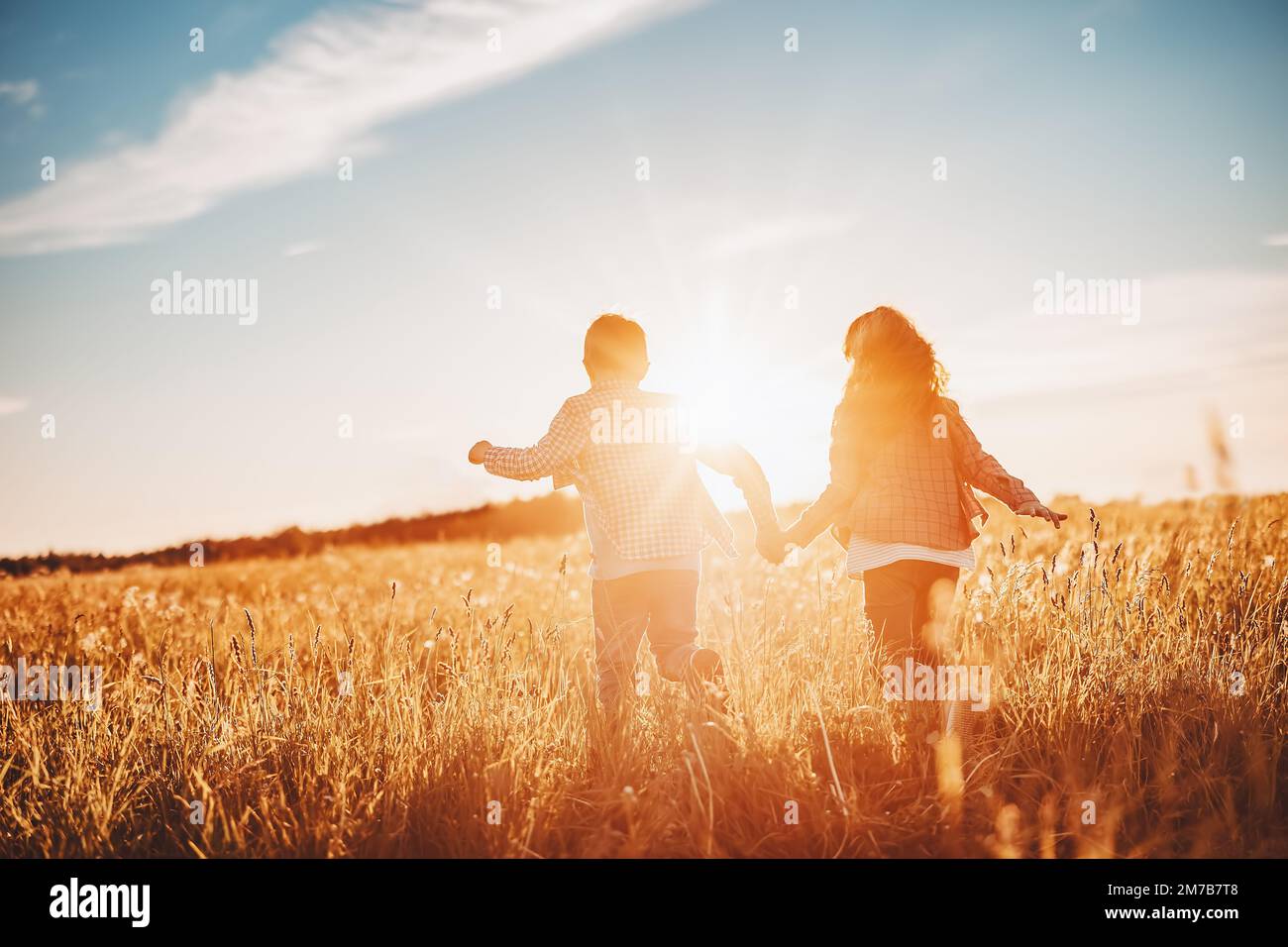 Two children running on the summer field by holding hands Stock Photo ...