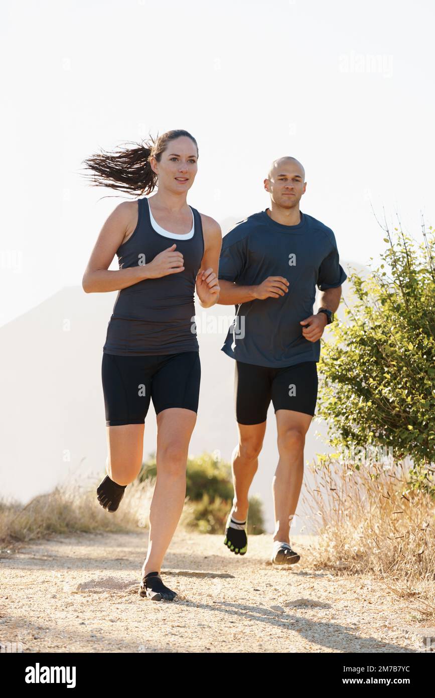 Running is always better with a partner. a young couple running along a ...