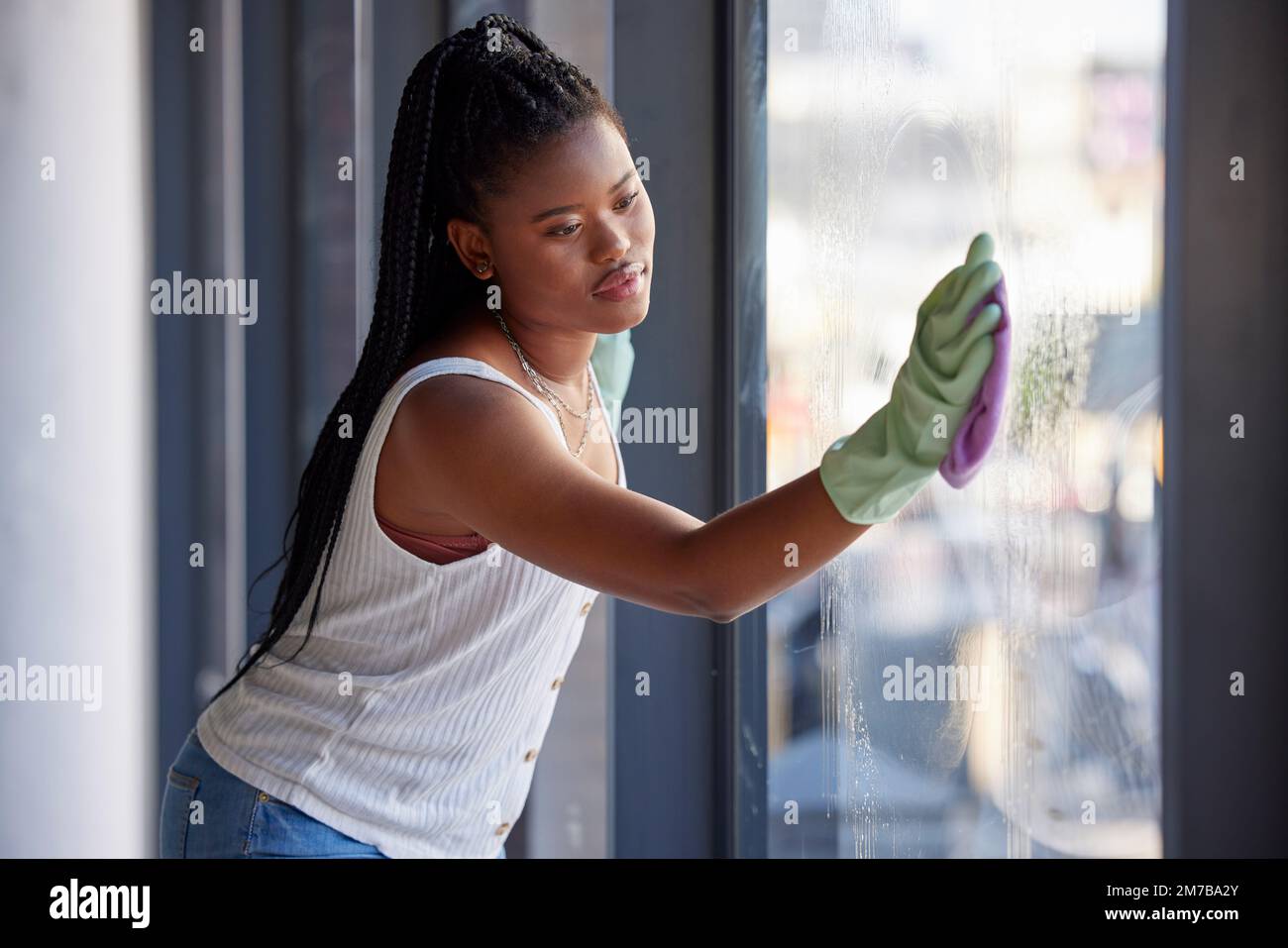 Housework, hygiene and black woman cleaning the window with cloth while ...