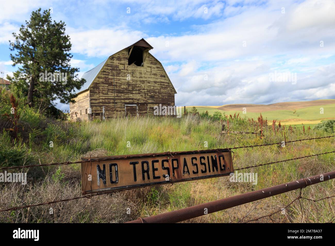 An old barn in Eastern Washington behind a rusty "no trespassing" sign ...