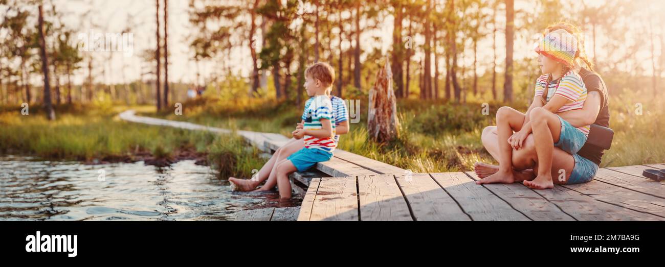 Mother with her children sitting on the pier of the swamp lake Stock ...