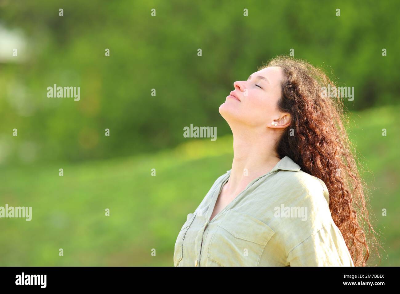Woman breathing fresh air in green background Stock Photo - Alamy
